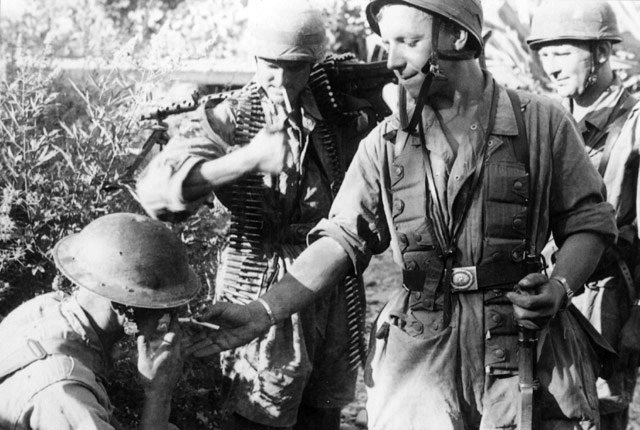 A German paratrooper gives a cigarette to a Canadian ally during the ...